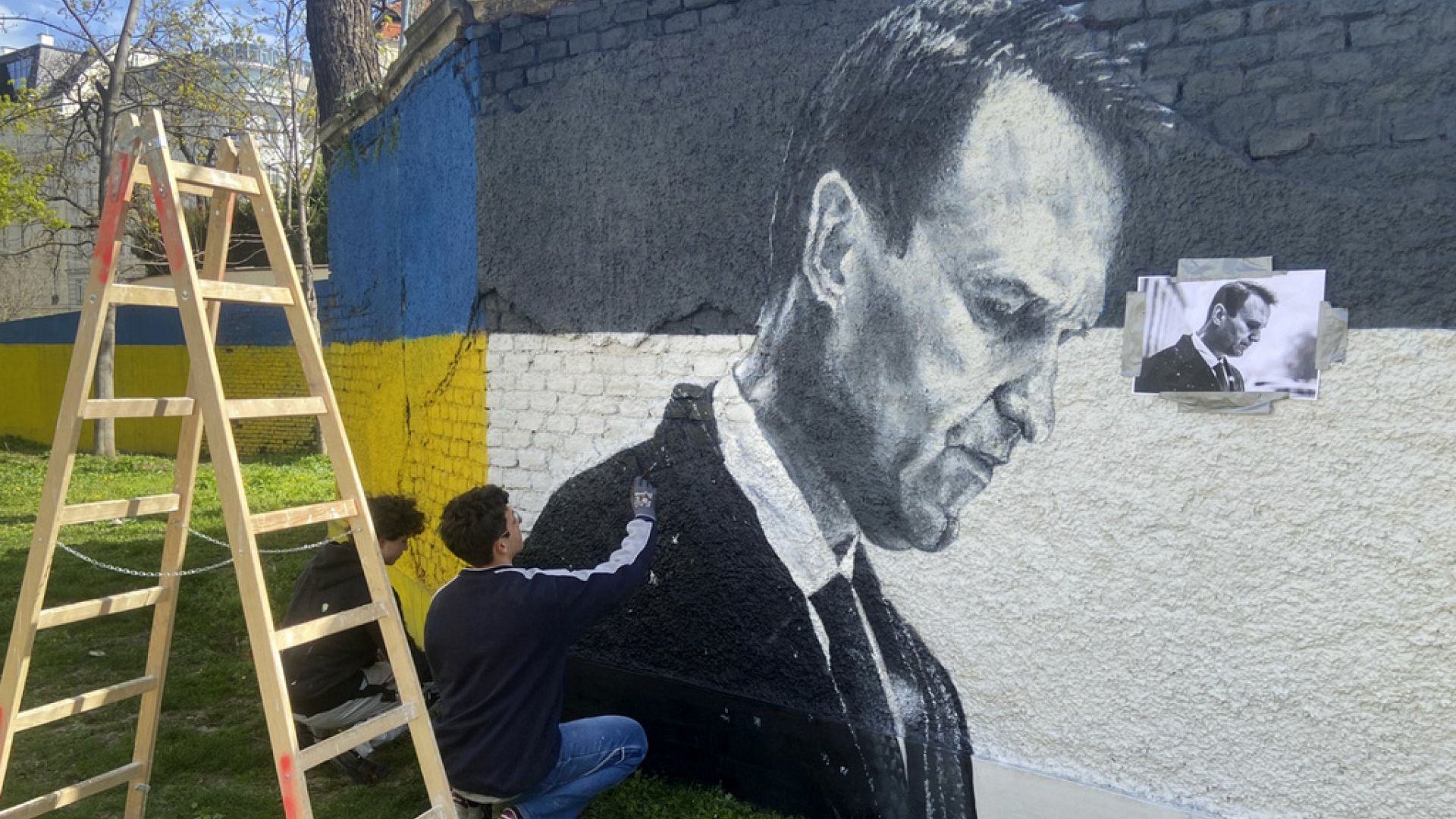 Artists spray-paint portraits of Alexei Navalny behind a Soviet ...
